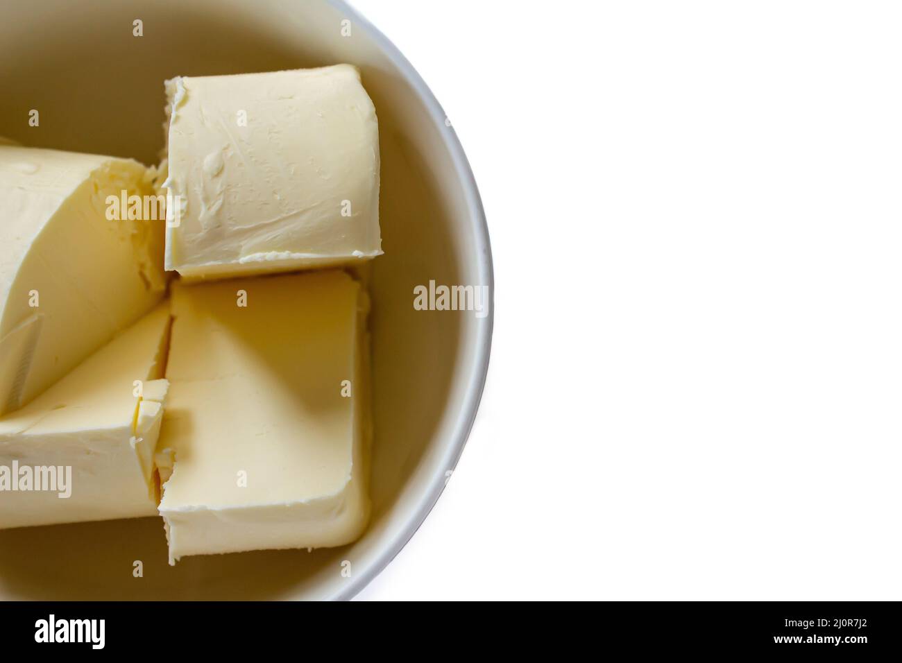 Butter pieces in bowl, isolated on white background. Top view of ...