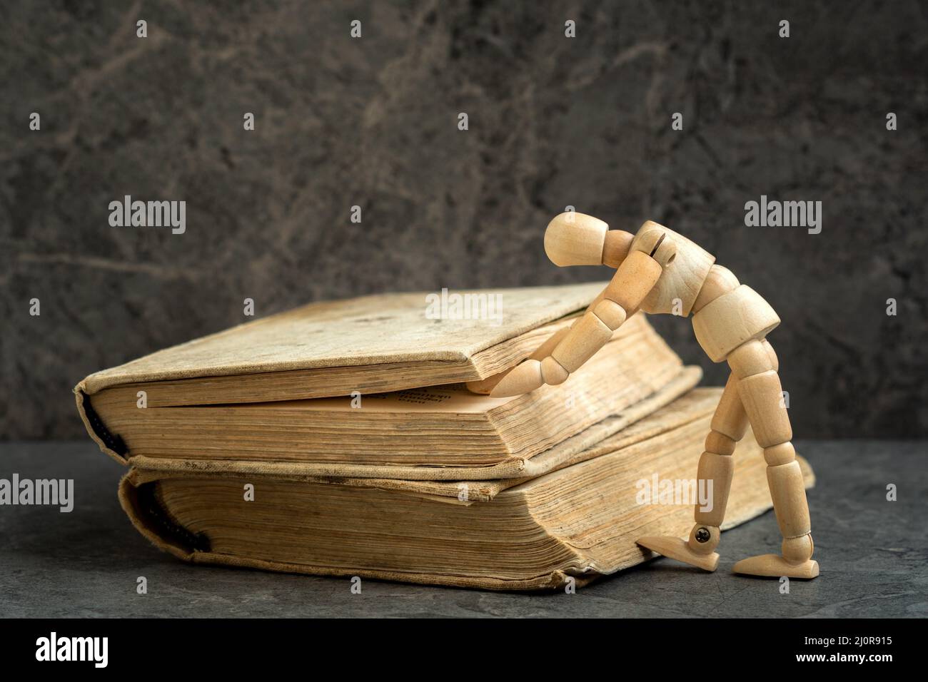 Wooden man trying to open book Stock Photo - Alamy