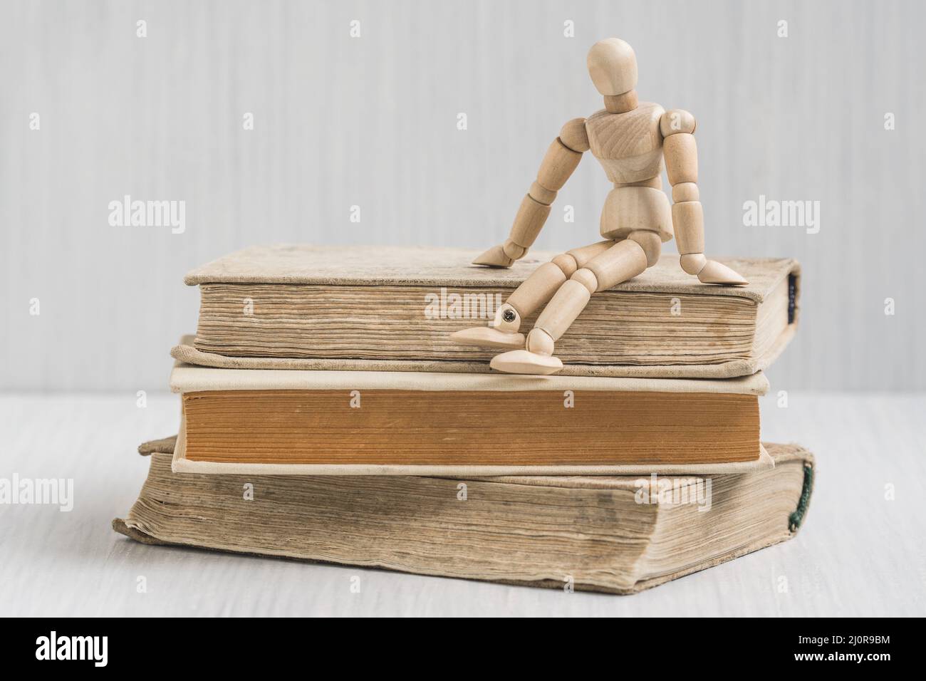 Wooden man sitting on the books stack Stock Photo - Alamy