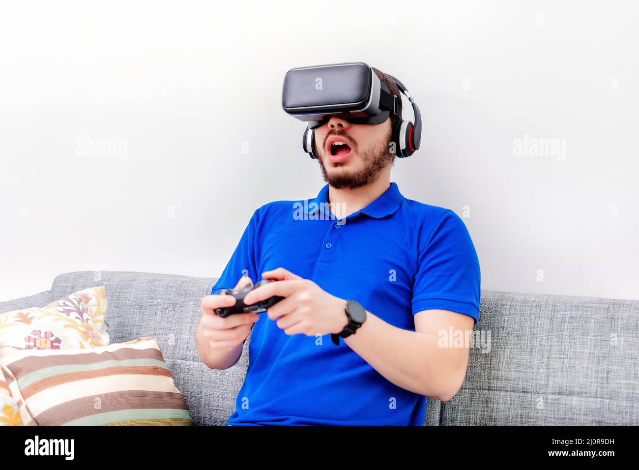 Young Middle Eastern gamer guy on a couch at home wearing virtual ...