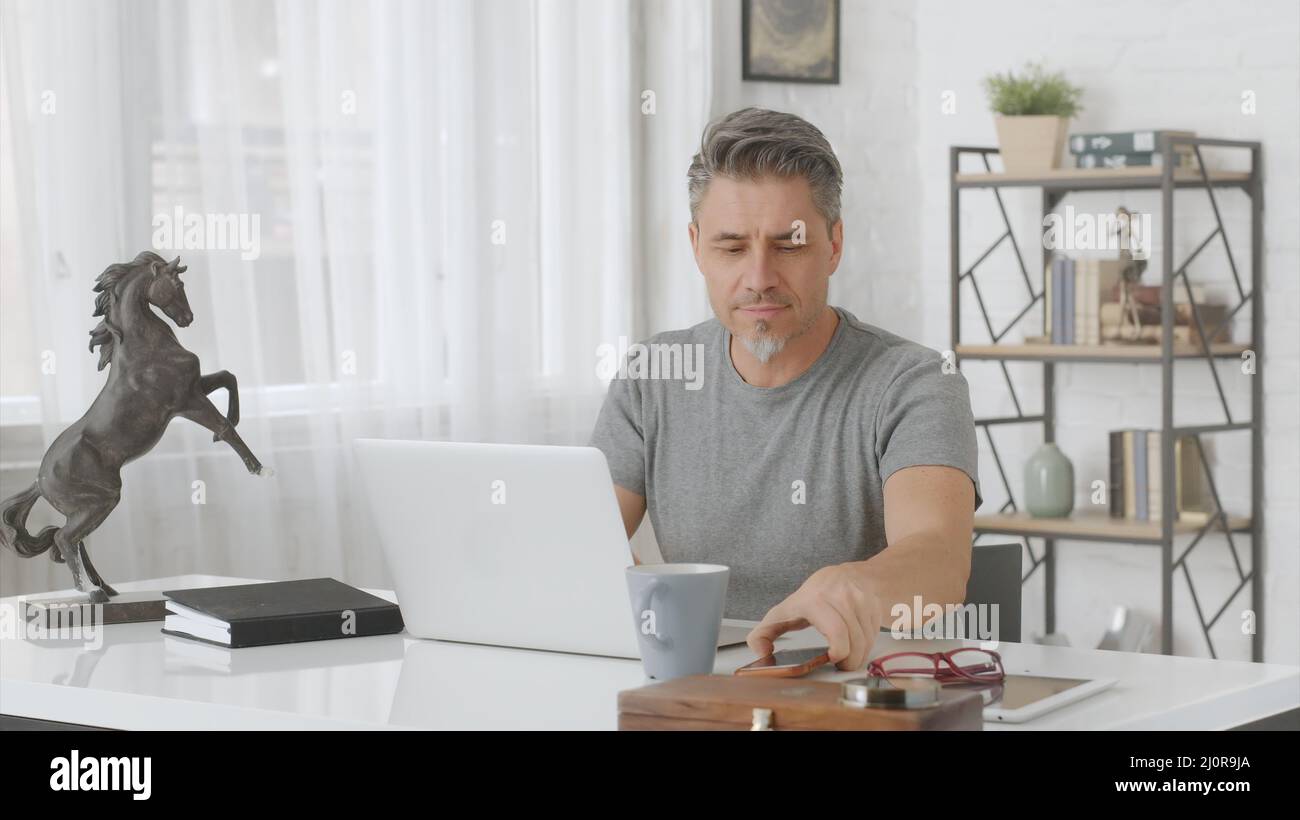 Happy older man with gray hair working at home in home office with ...