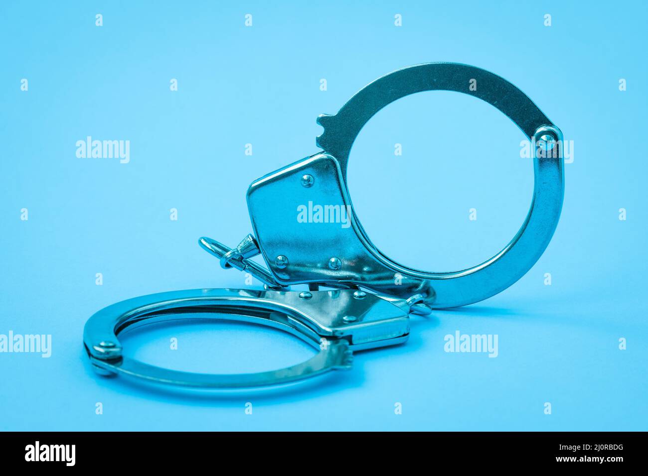 Handcuffs lying on the blue background Stock Photo - Alamy