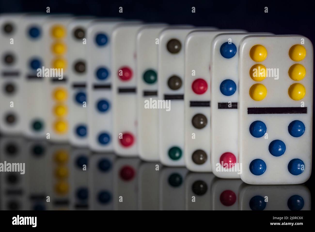 Dominoes with colorful dots standing in a line showing depth of field ...