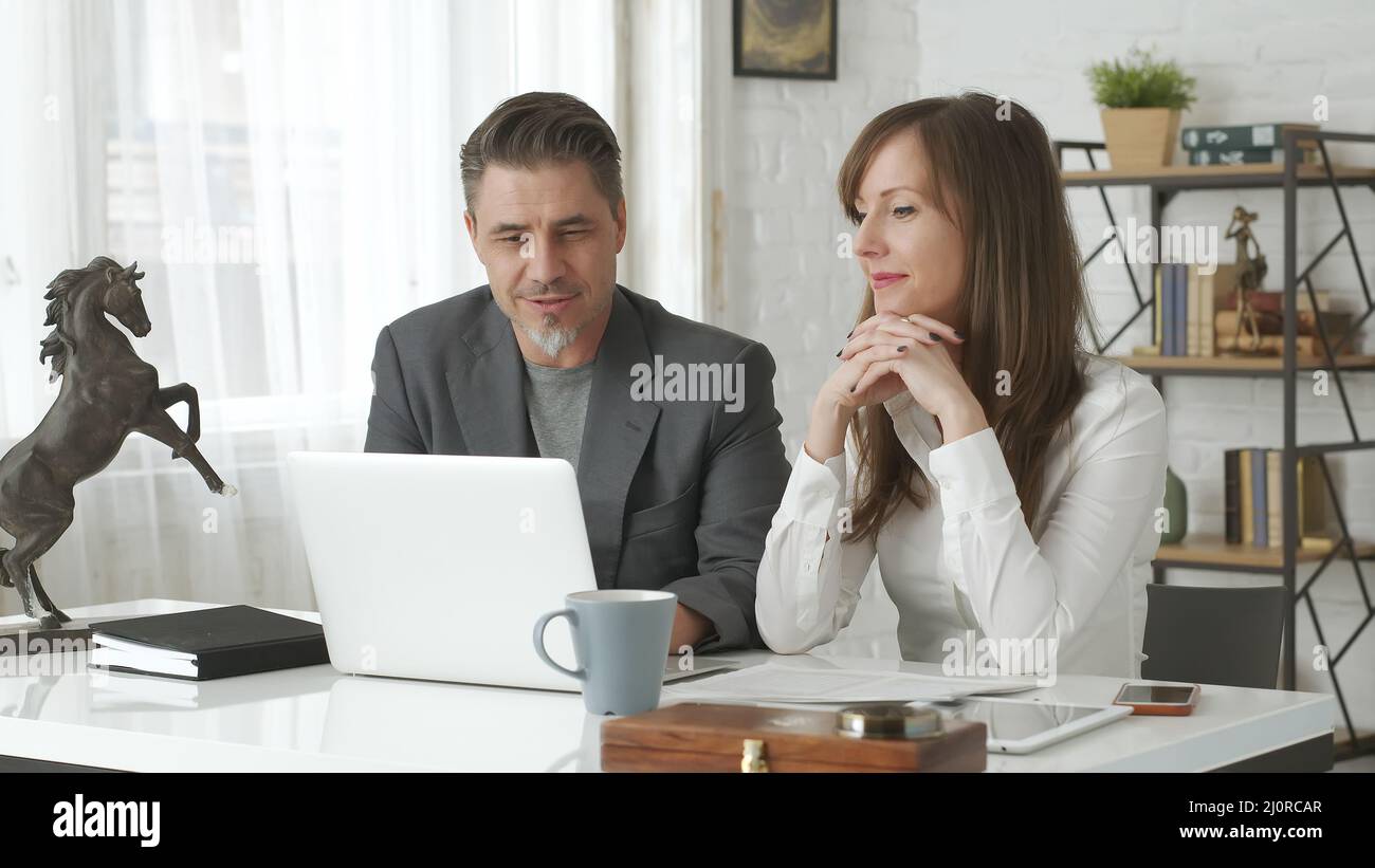 Happy business people working at desk using laptop computer, talking ...