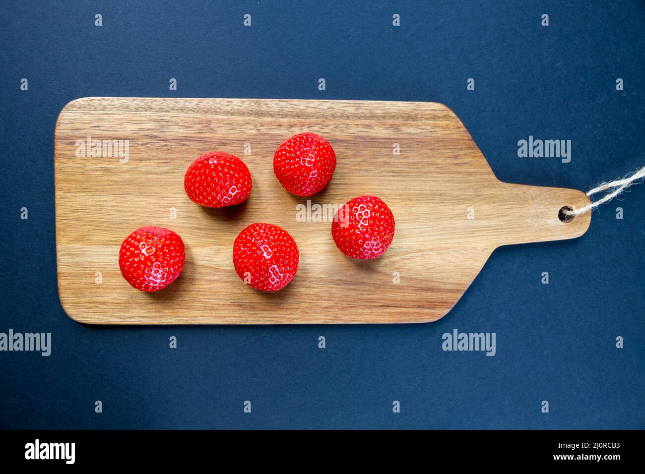 Strawberries on a cutting board. Black background Stock Photo - Alamy