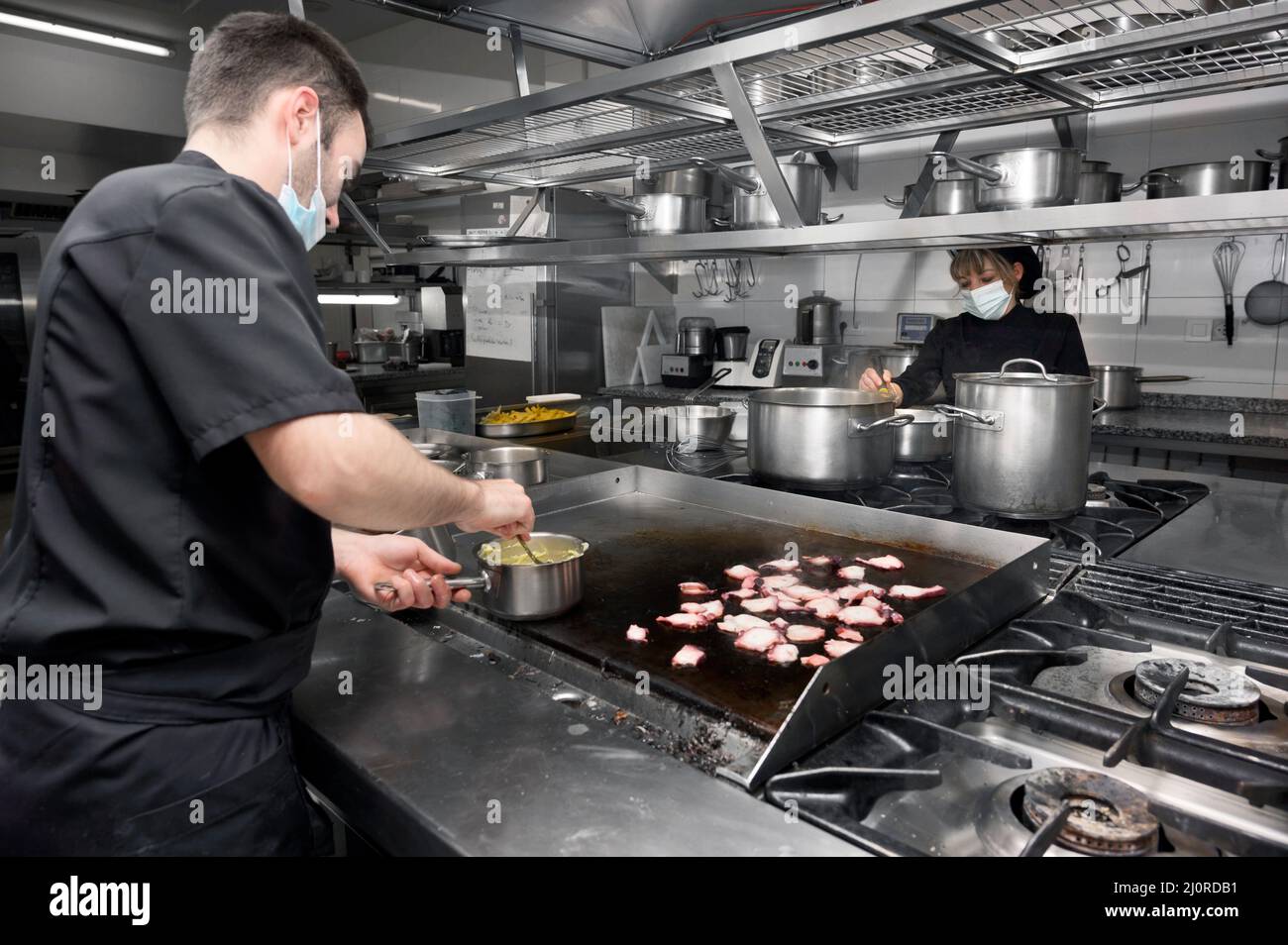 Group of chefs cooking together in the kitchen at restaurant wearing ...