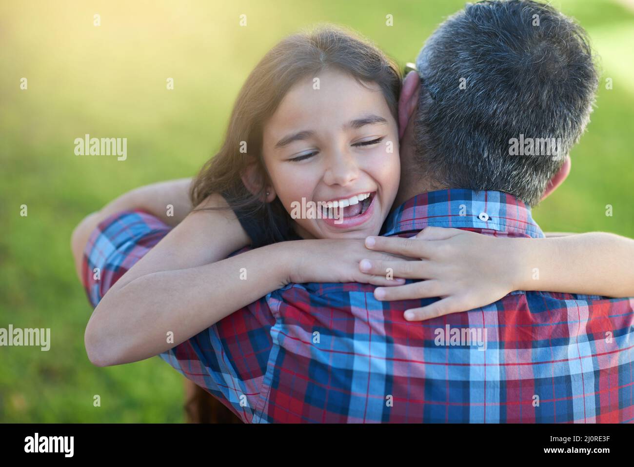 Daddys home. Shot of a happy little girl hugging her father at home ...