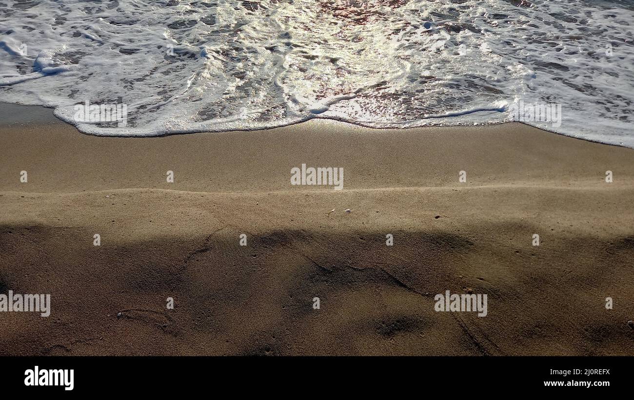Closeup shot of the waves on the sandy shore at sunset in spring Stock ...