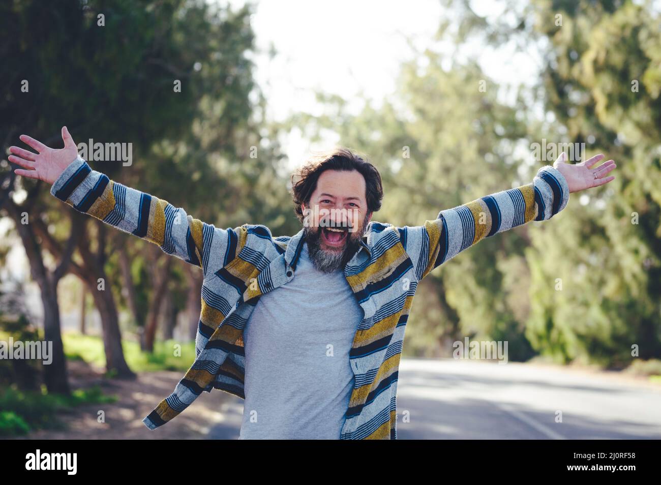 Crazy overjoyed adult man with arms outstretched smile and laugh alone ...