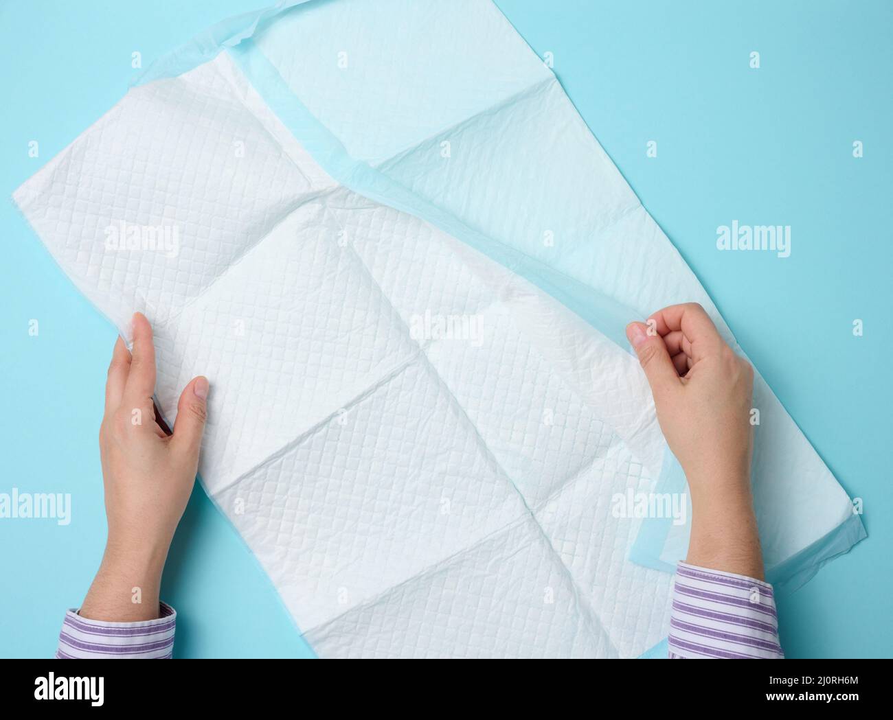 Female hand holds a disposable medical diaper on a blue background ...