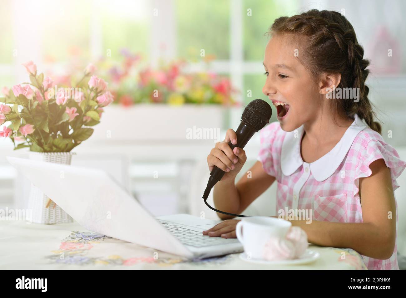 Portrait of little girl with laptop singing karaoke Stock Photo - Alamy