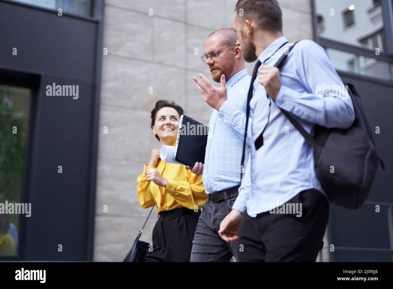 Three white collar workers in formal wear walking along the street in ...