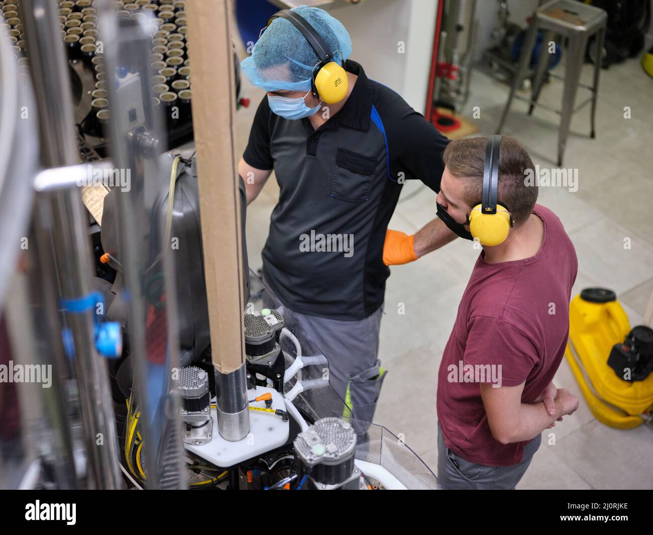 Workers wearing mask checking the machinery of a craft beer factory ...