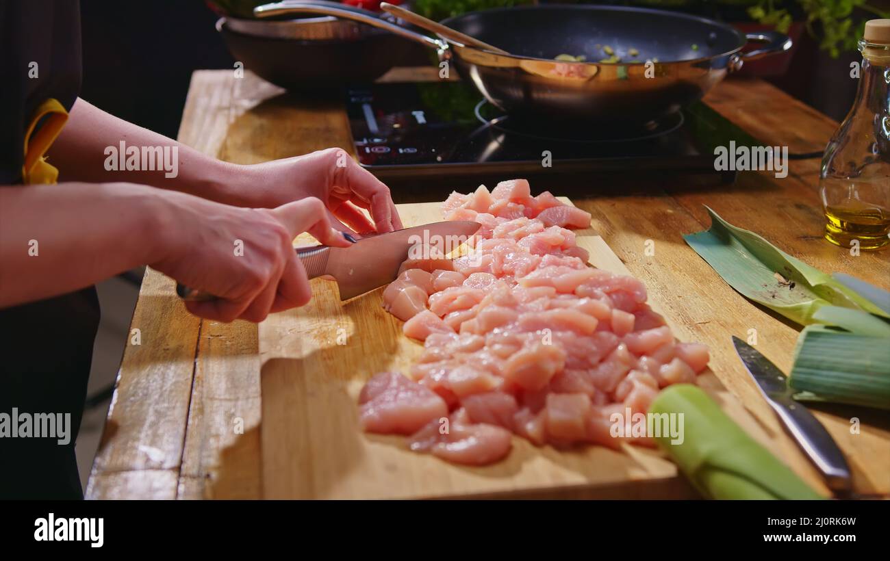 Woman slicing meat for cooking on kitchen table. Closeup hands. Cosy ...