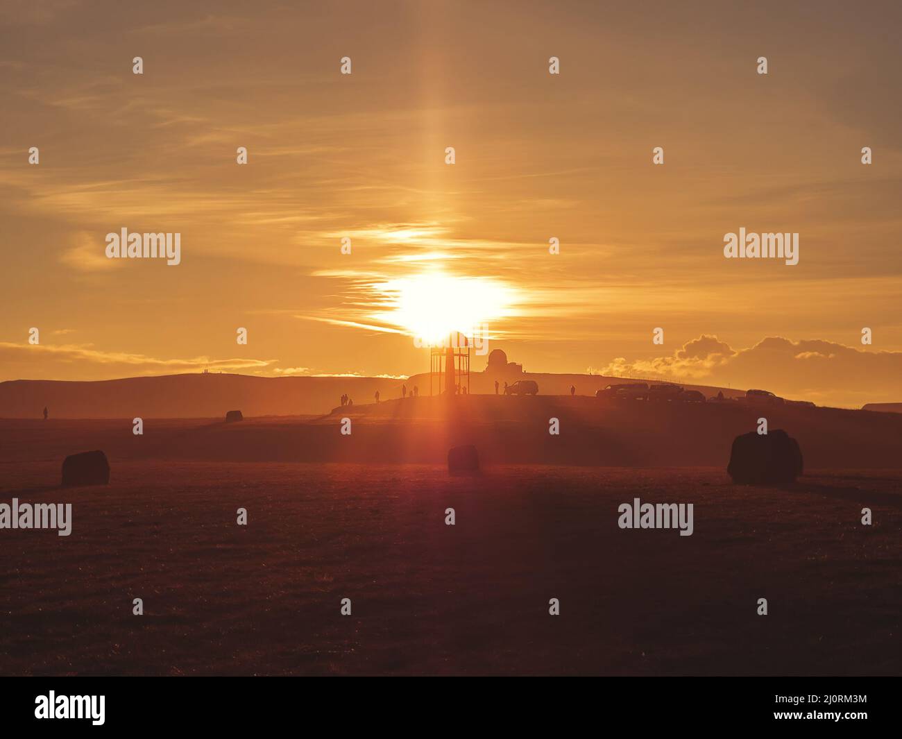 The outline of fields and haystacks with silhouettes of people and cars ...
