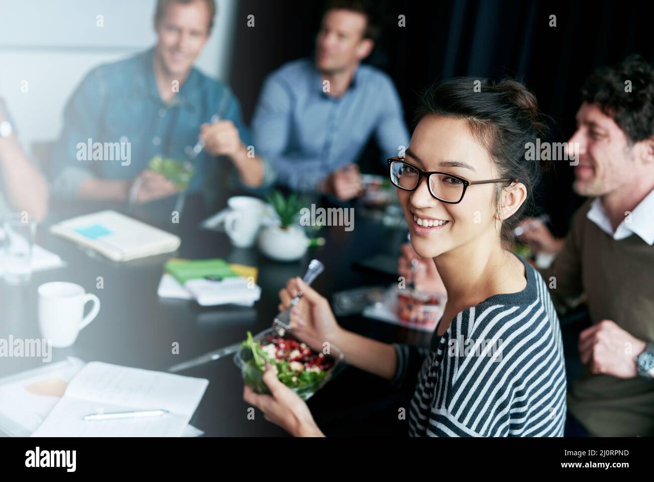 Enjoying a team lunch. Portrait of a young office worker eating lunch ...