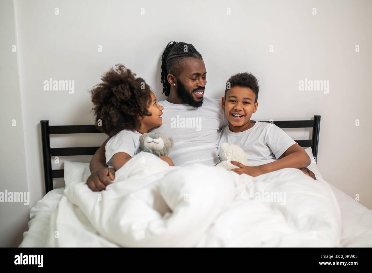 Man hugging children sitting in bed Stock Photo - Alamy