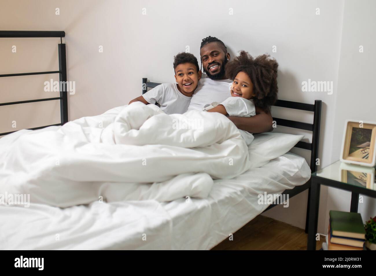 Man hugging kids in bed smiling at camera Stock Photo - Alamy