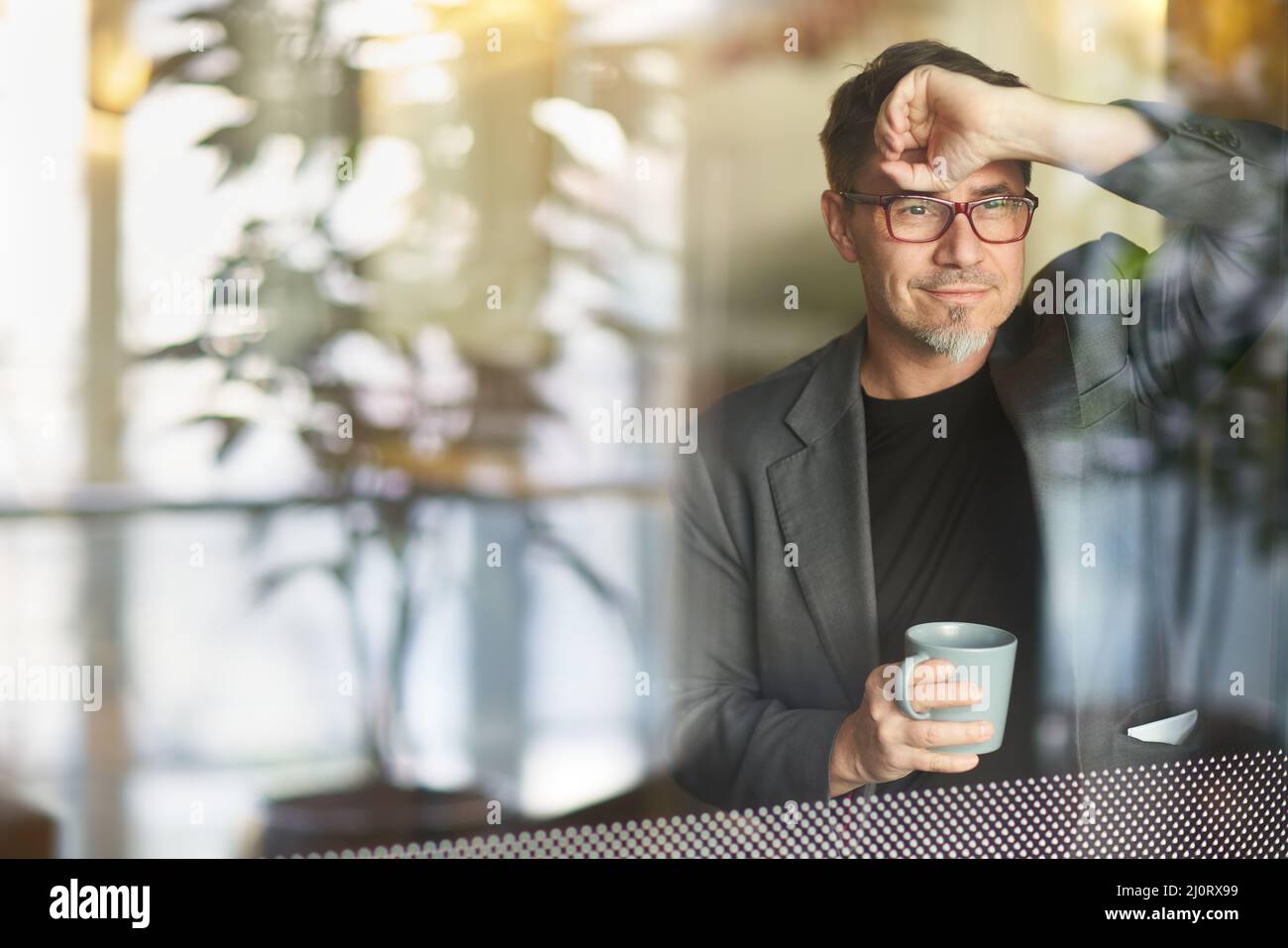 Older businessman in corporate workplace taking break and drinking ...