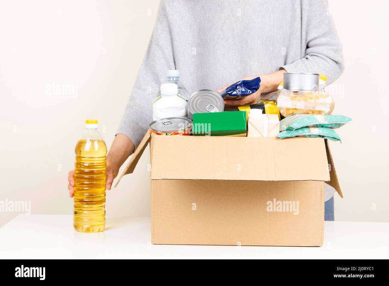 Volunteer hands collecting food into donation box full of grocery ...
