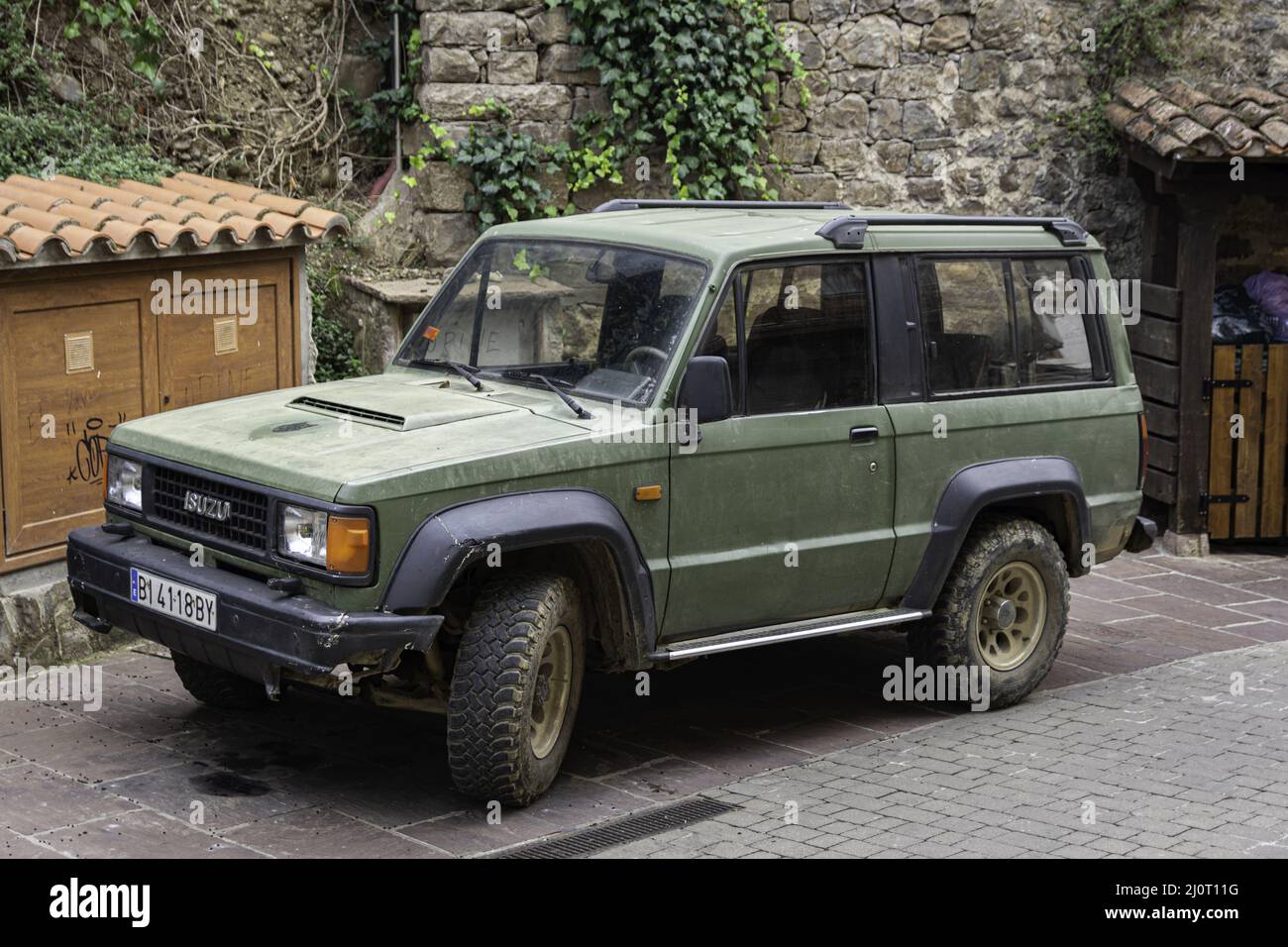 Old town off-road car parked on the street is painted camouflage green ...
