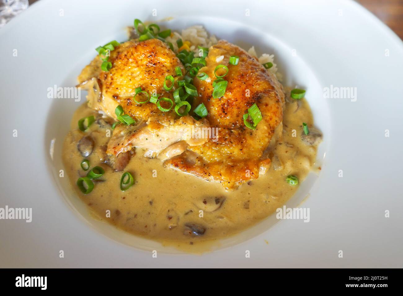 Sautéed boned chicken thighs on a bed of rice with peas and corn served ...