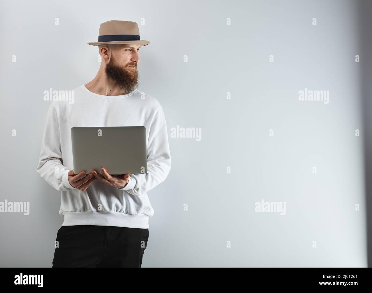 Man holding laptop leaning against white wall hi-res stock photography ...