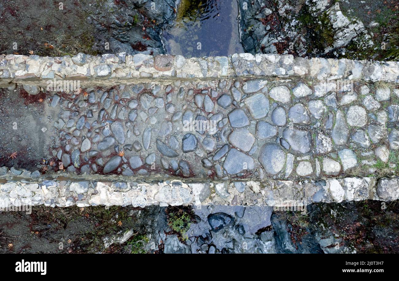 Aerial drone scenic of a medieval stoned bridge with water flowing in ...