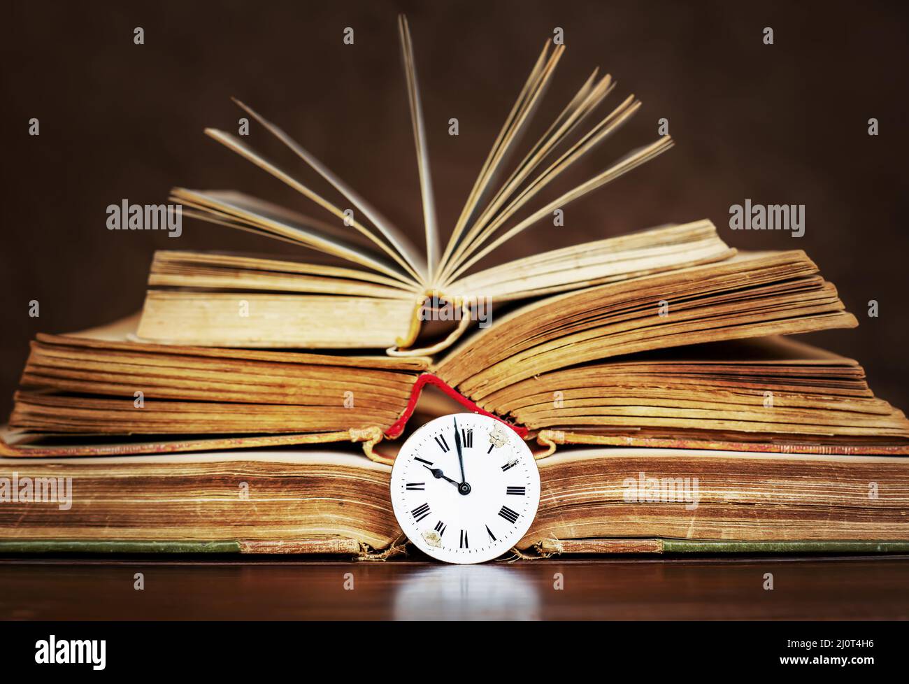 Old opened books and vintage antique clock face. Story time ...