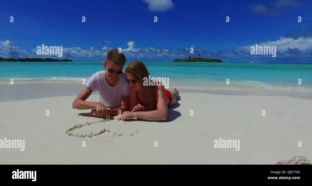 Couple on beach in Rasdhoo Atoll, Rasdhoo Island, The Maldives drawing heart on the sand Stock ...