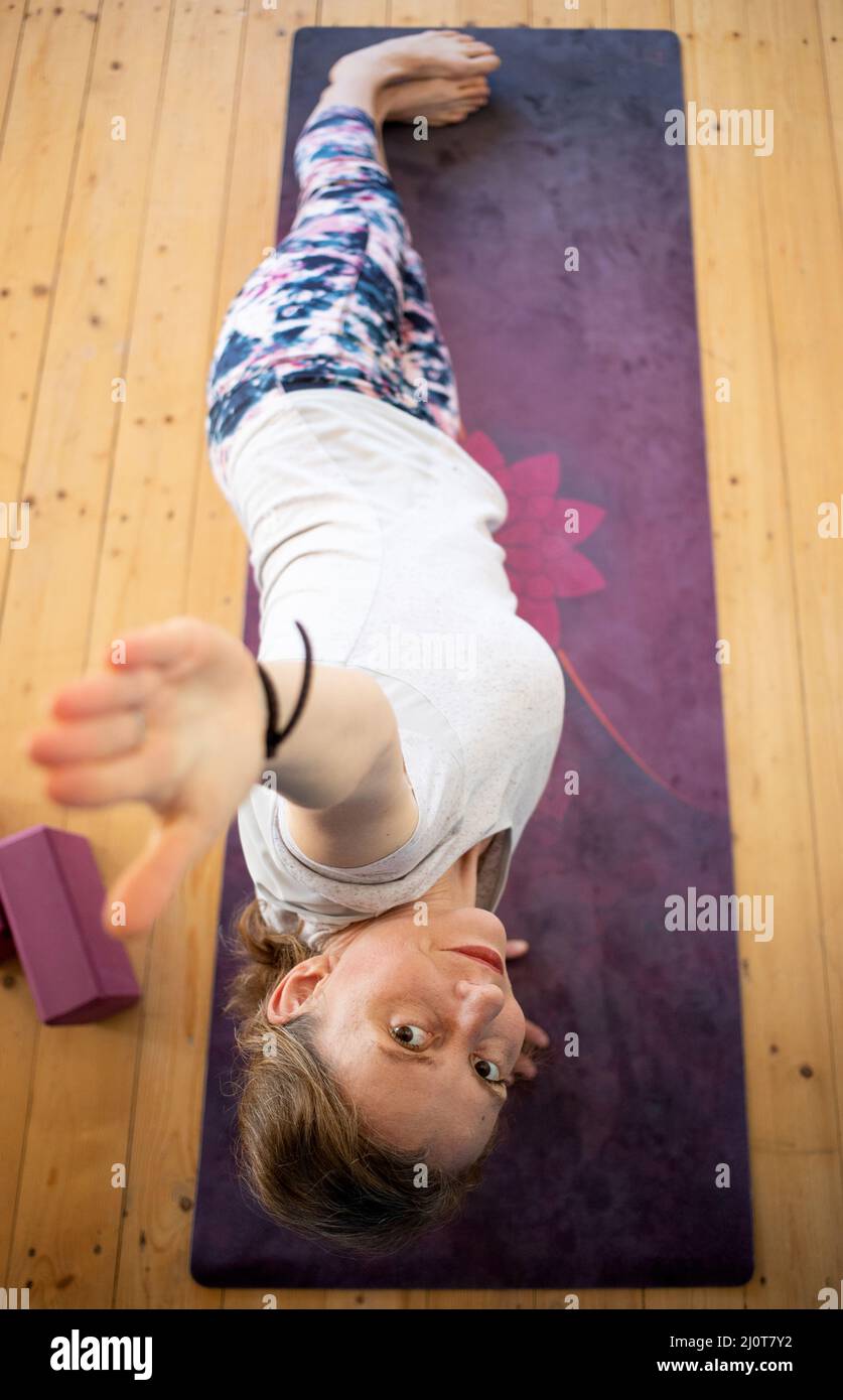 top view of woman doing yoga at home in a side plank balancing pose ...