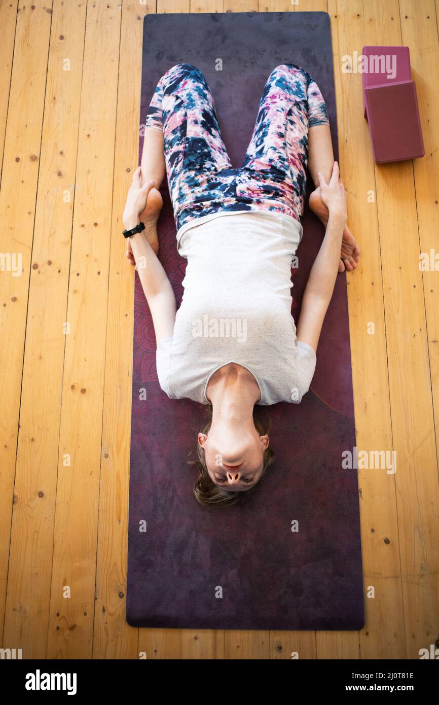 top view of woman doing yoga at home Supta V‏irasana or reclining hero ...