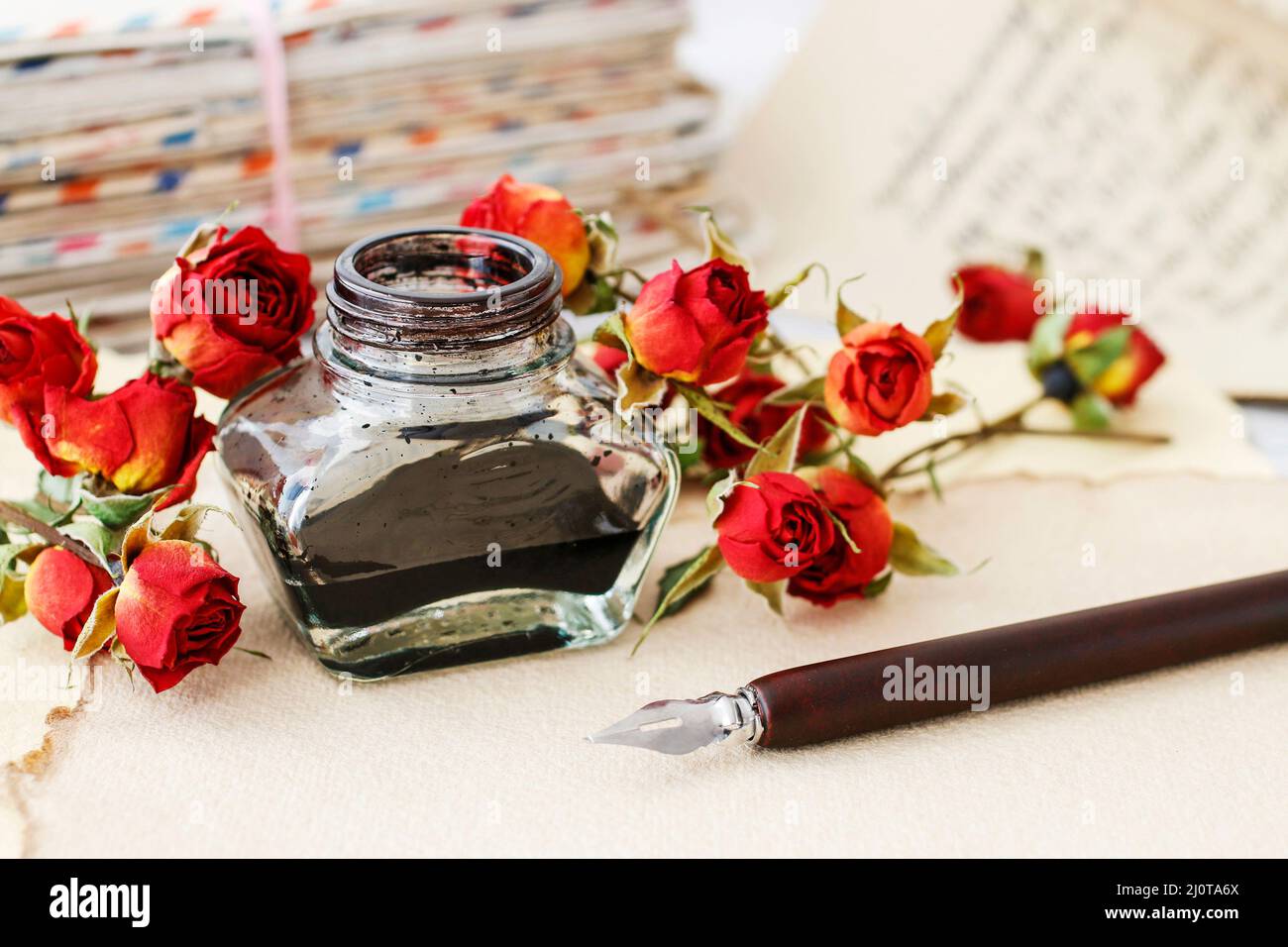 Inkwell, pen, dried roses and stack of vintage letters. Retro style ...