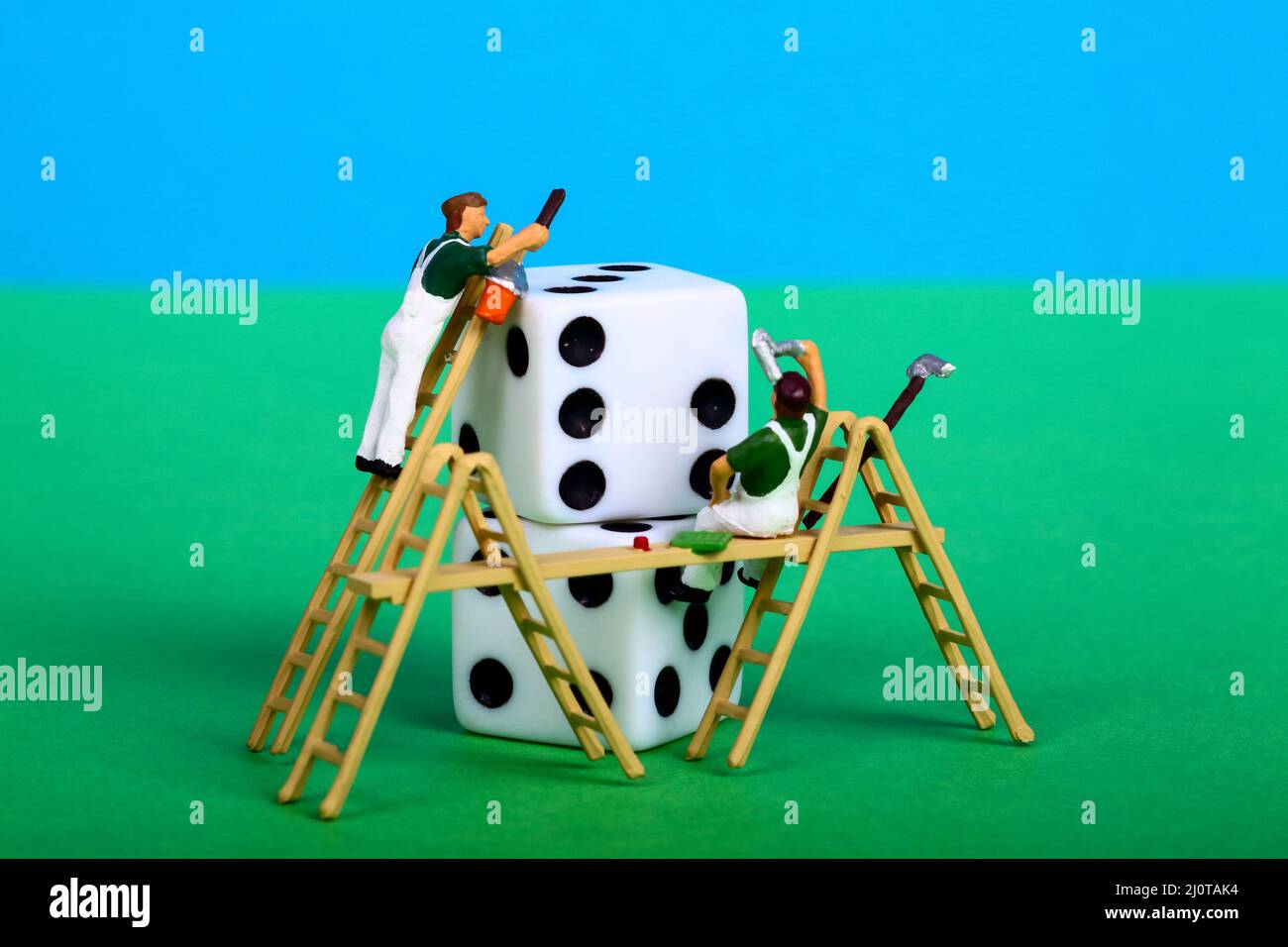 Conceptual image of miniature figure people painting the spots on dice ...