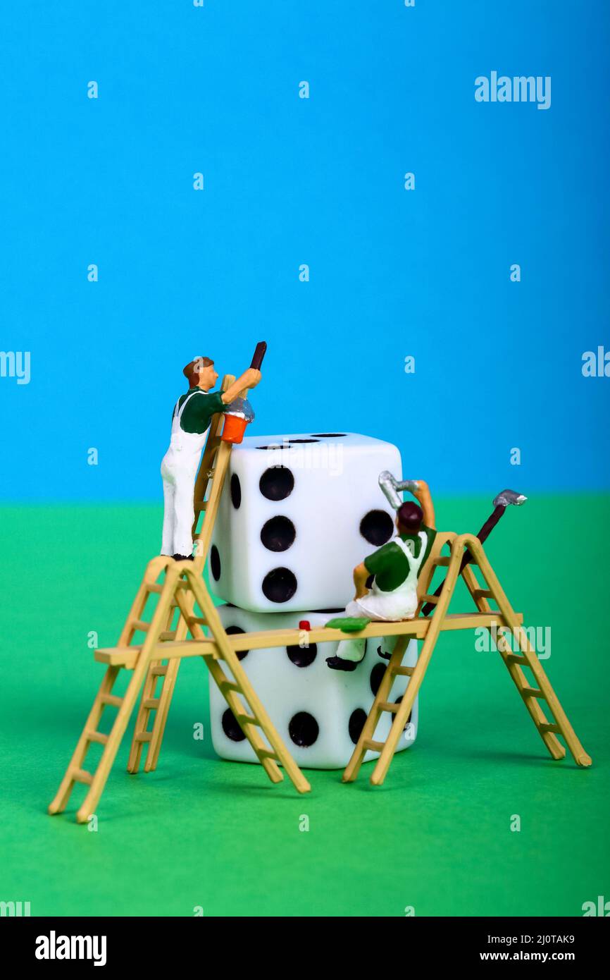 Conceptual image of miniature figure people painting the spots on dice ...
