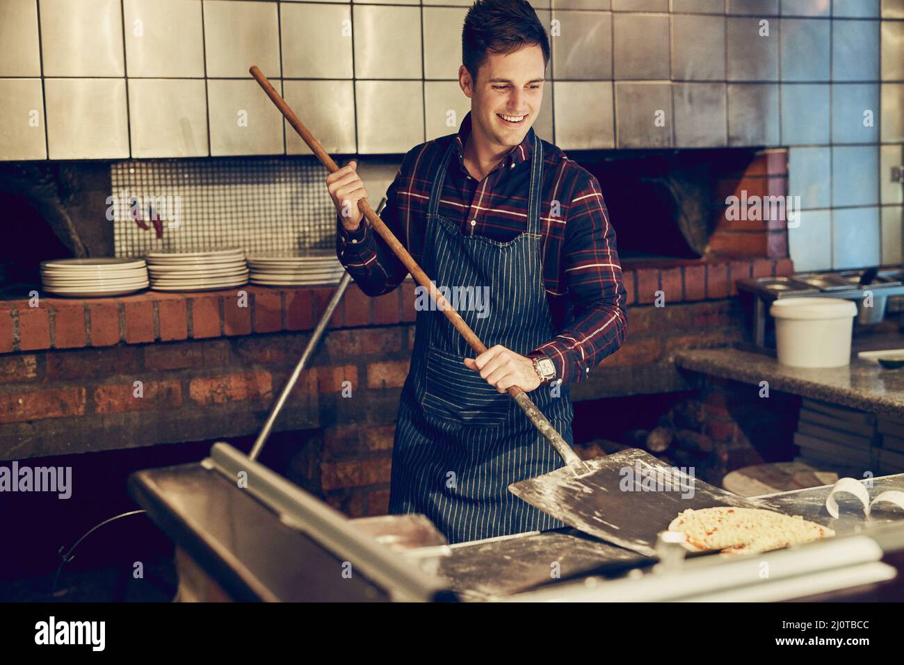 Master pizza maker at work. Shot of a young man using a peel while ...