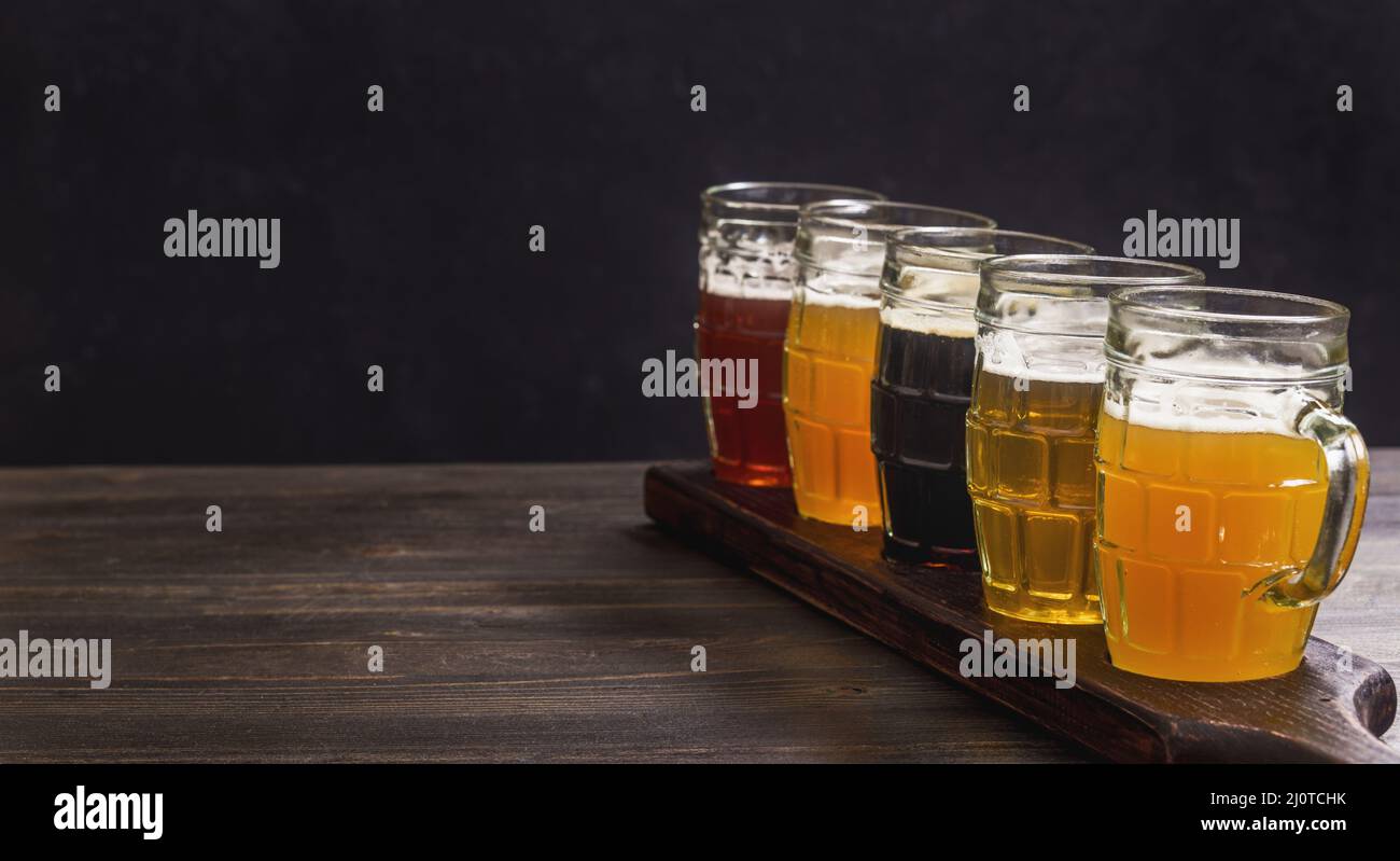 Tasting set of different types of beer on a table against a dark ...
