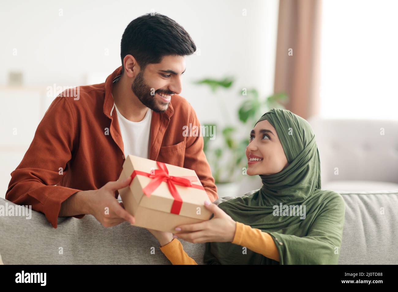 Muslim Husband Giving Present Box To Happy Wife Sitting Indoors Stock ...