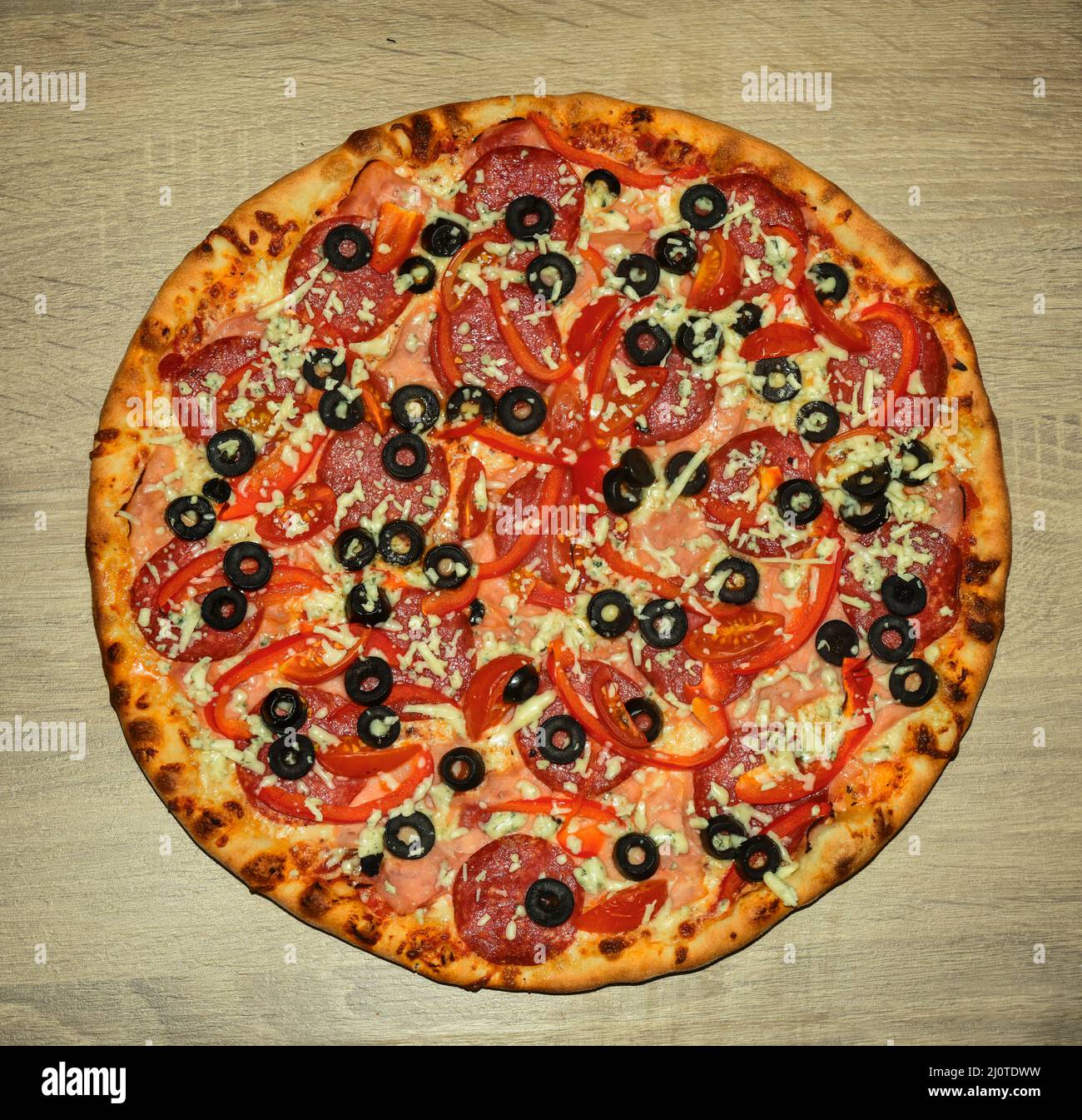 Baked, round pizza with salami, pepperoni and sliced olives with brown ...