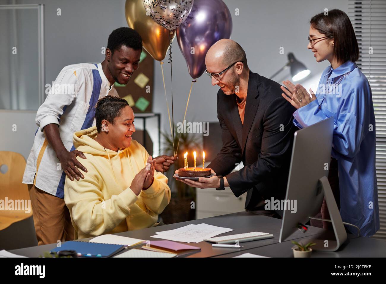 Diverse group of colleagues bringing Birthday cake with candles ...