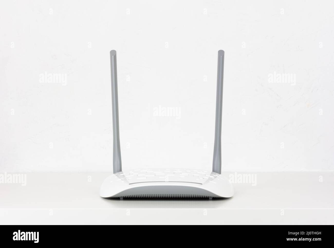 New white Wi fi router on a table against a white wall with a copy ...