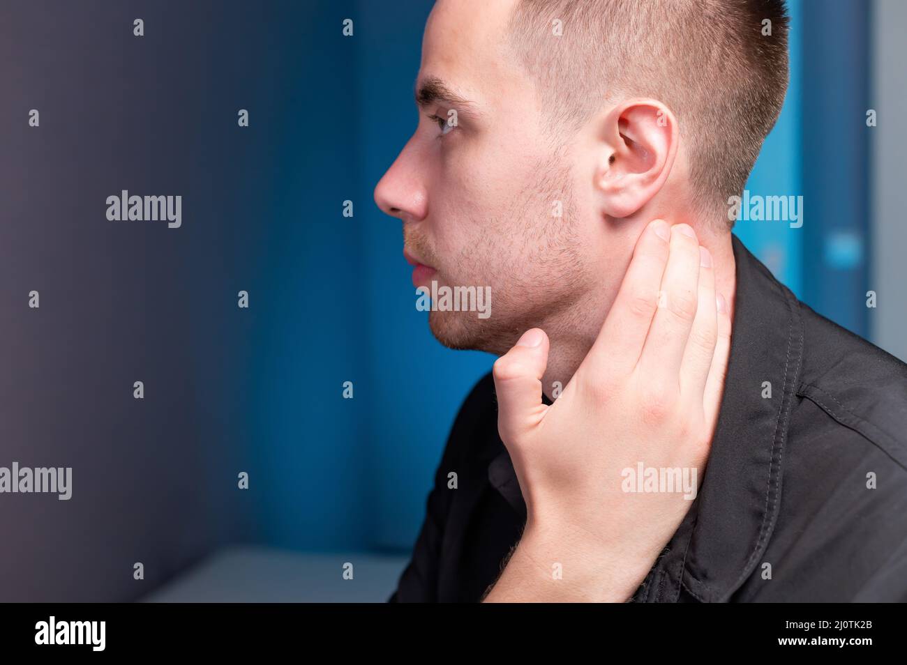 Close-up of a man holding his neck with his hand. Neck pain and self ...