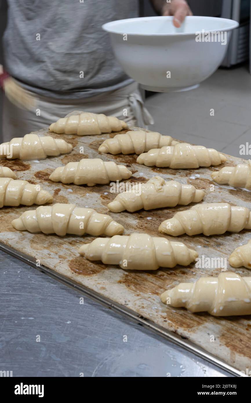 Artisan baker and pastry chef. Chef baker preparing croissants in a ...