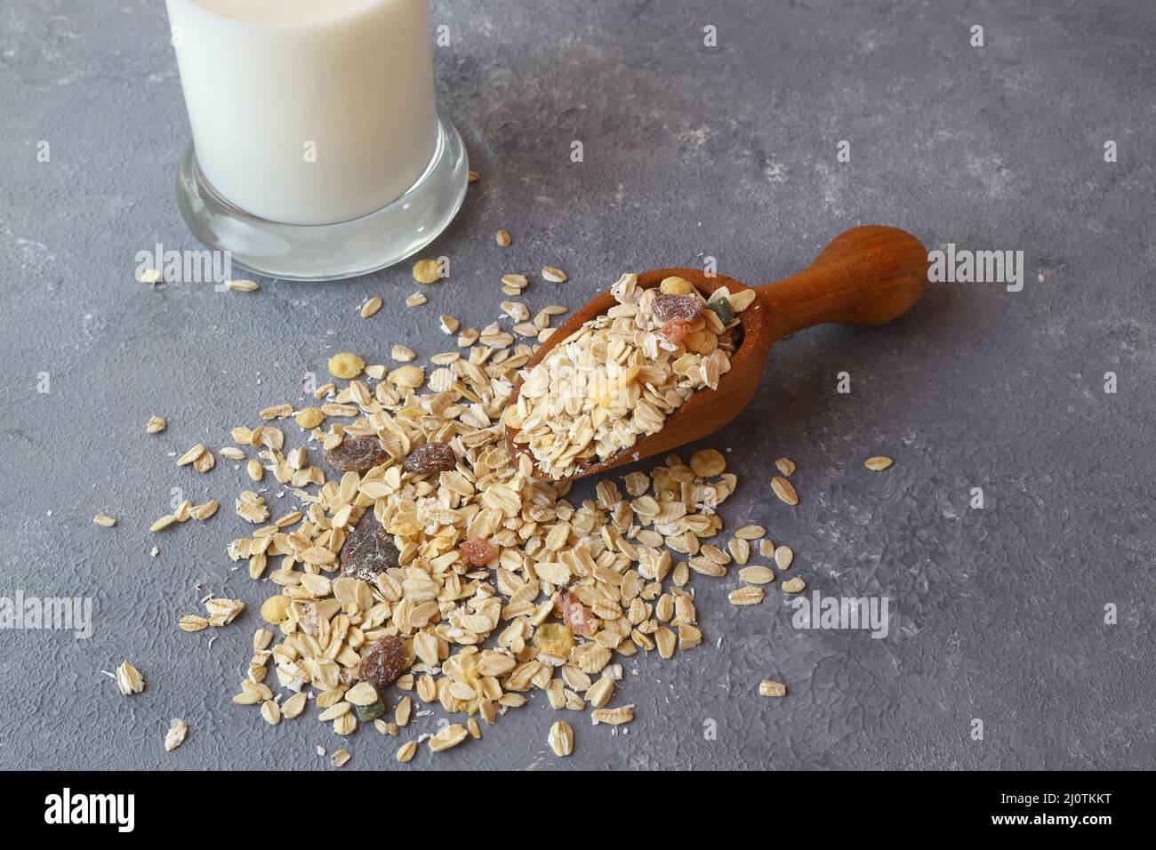 Oatmeal in a green bowl with a glass of milk on a gray background. A ...