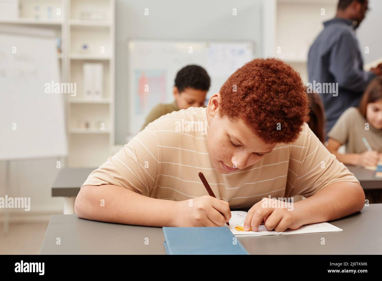 Portrait of red haired teenage boy working hard while studying in ...