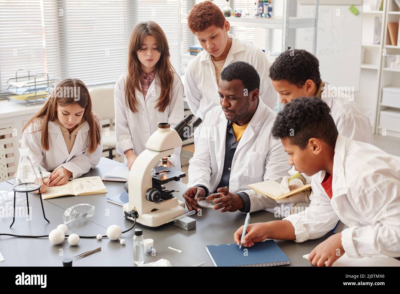 Portrait of diverse group of children doing experiments with teacher in ...