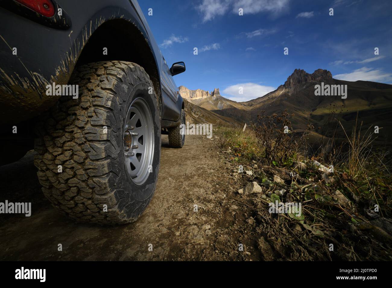 Close-up A large off-road all-terrain car wheel stands on a rough road ...