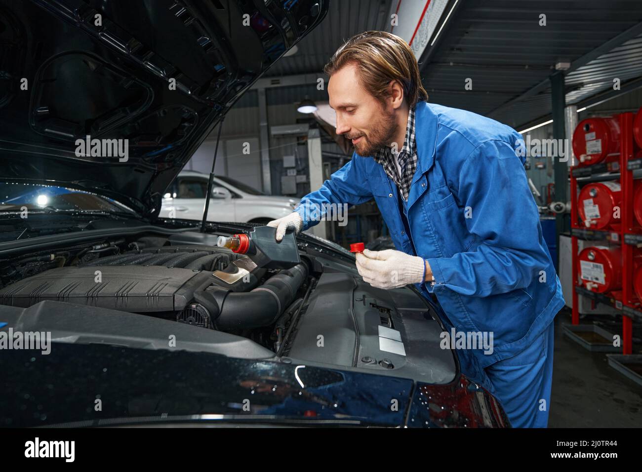 Car mechanic performing car maintenance at service station Stock Photo ...
