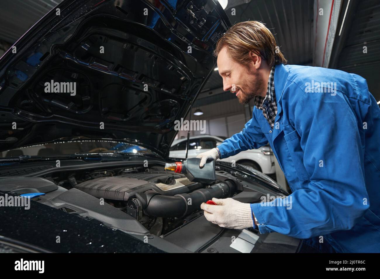 Mechanic performing car maintenance at service station Stock Photo - Alamy