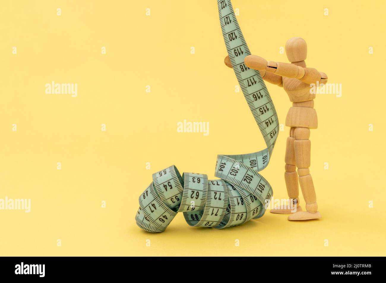 Wooden man holding measure tape Stock Photo - Alamy